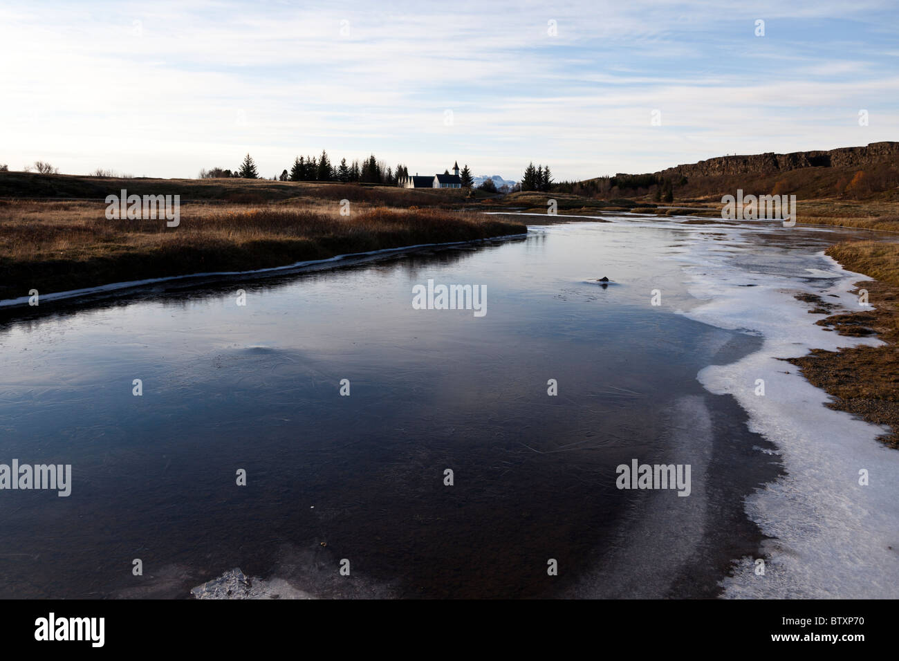 Semi-frozen river Oxara with Thingvalla Kirkja church in the distance ...