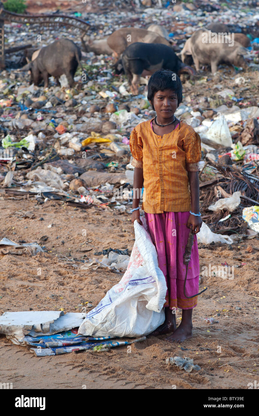 Poor Indian girl with a sack picking through an open rubbish tip ...