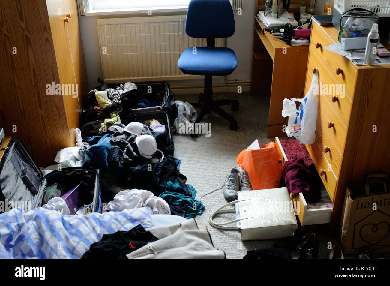 Messy and very untidy woman's bedroom with clothes and luggage ...