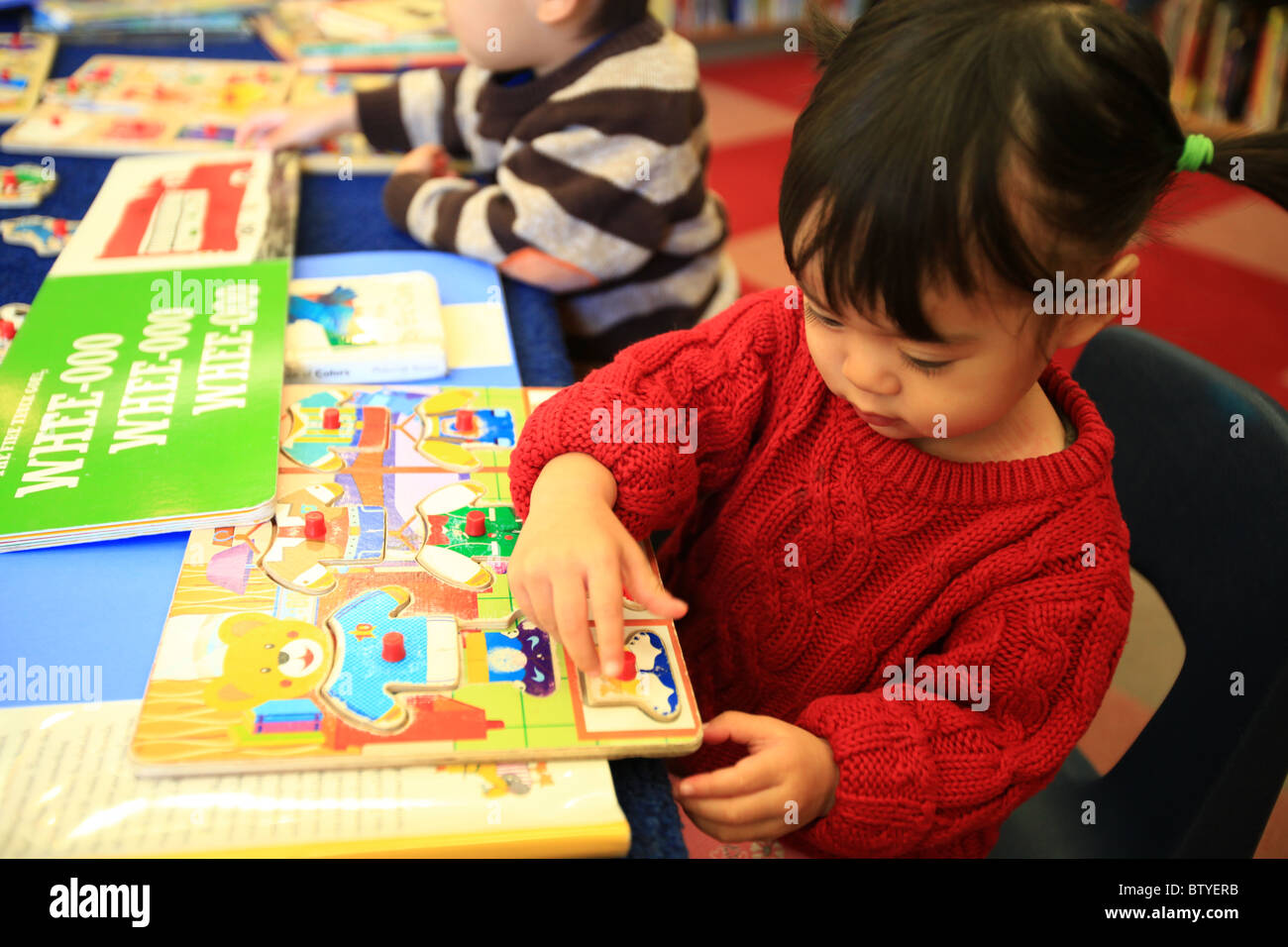 Little girl reading books in library Stock Photo - Alamy