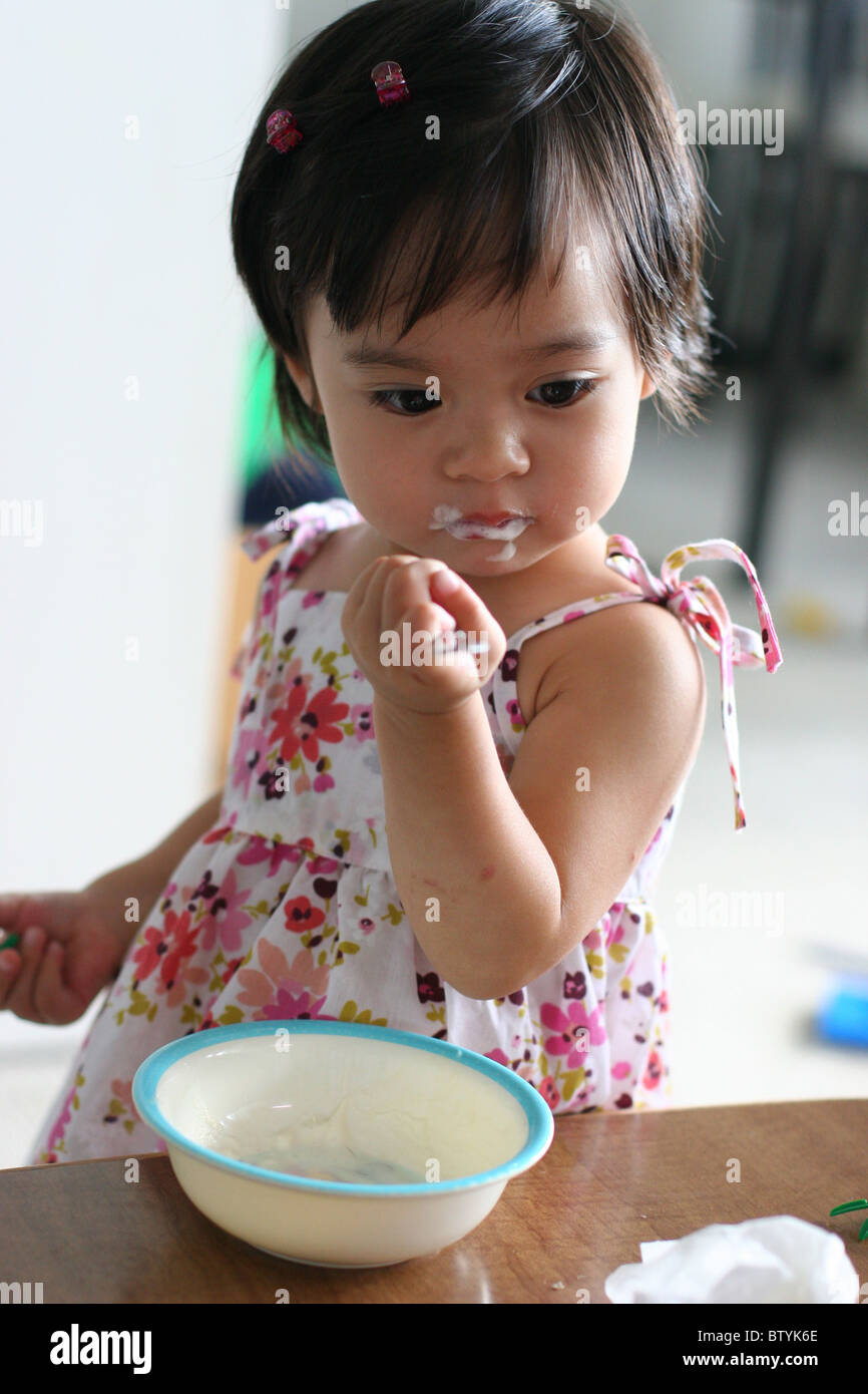 Adorable baby girl eating cream Stock Photo - Alamy