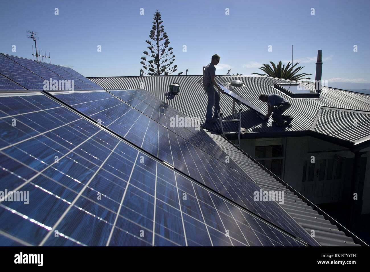 Photovoltaic solar panels being fitted by tradesmen to a house in ...