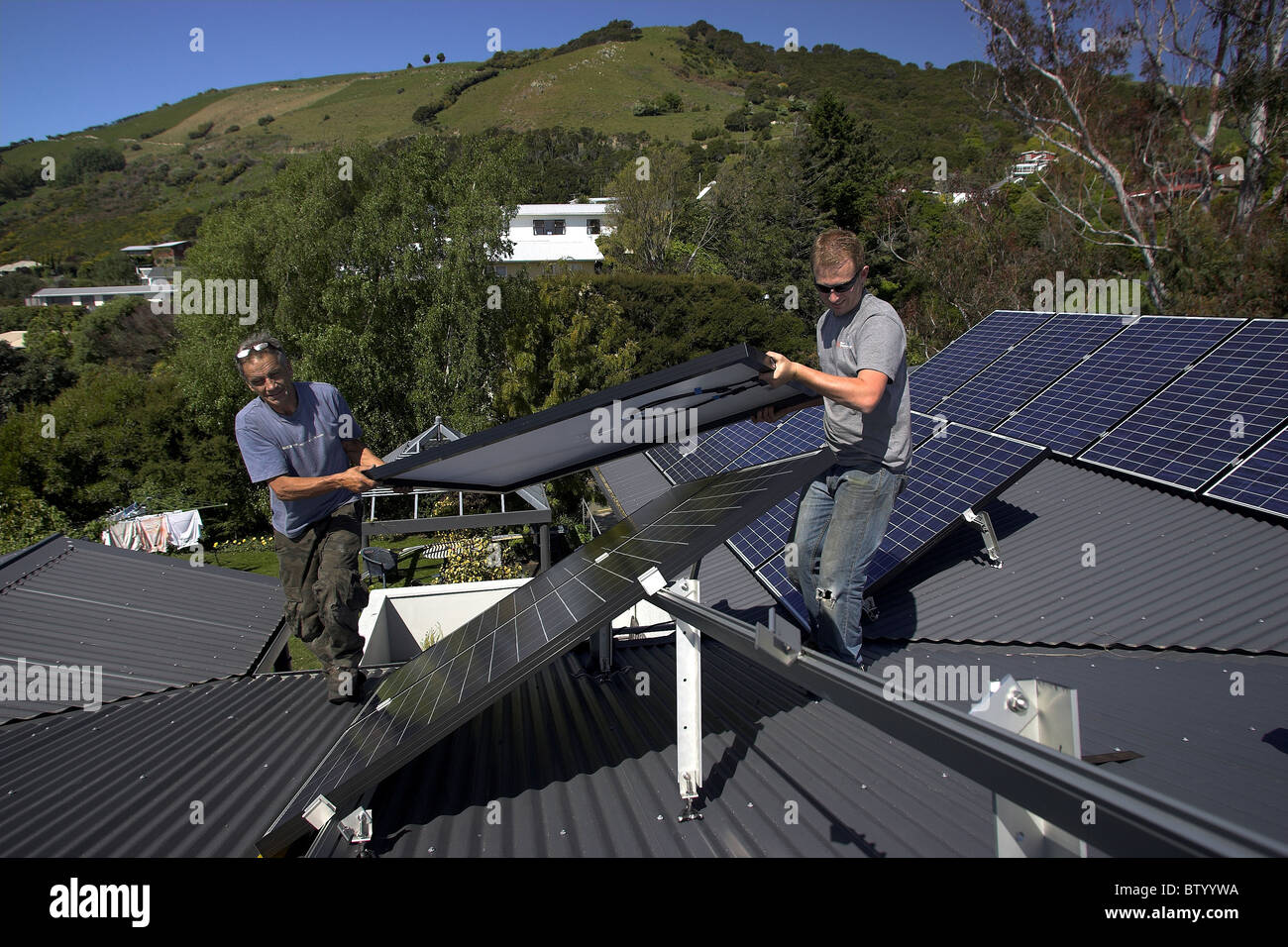 Photovoltaic solar panels being fitted by tradesmen to a house in ...