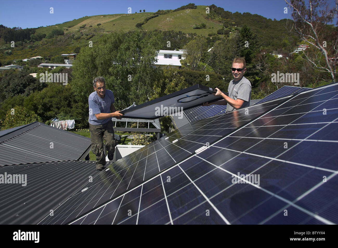 Photovoltaic solar panels being fitted by tradesmen to a house in ...