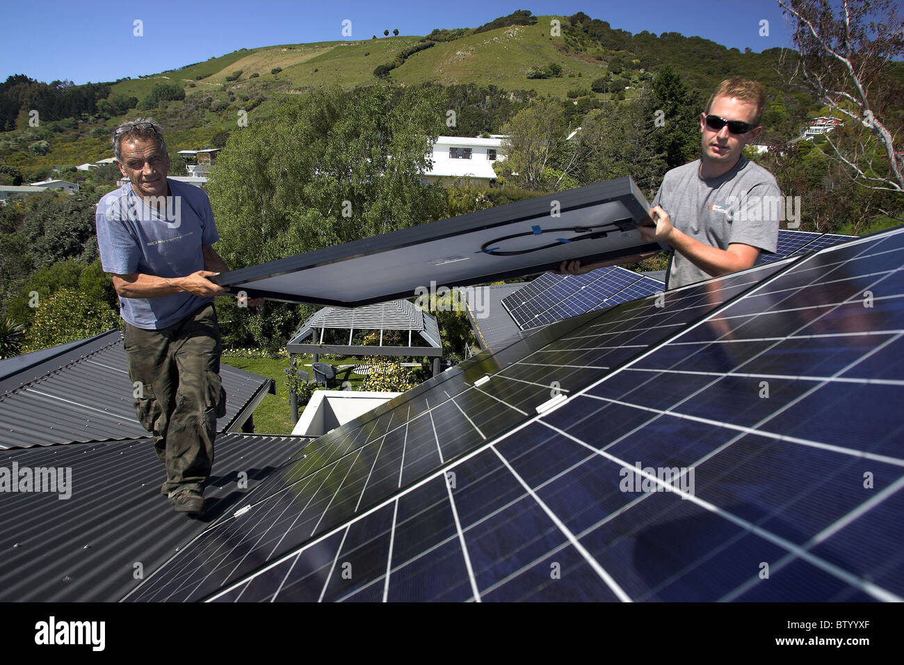 Photovoltaic solar panels being fitted by tradesmen to a house in ...