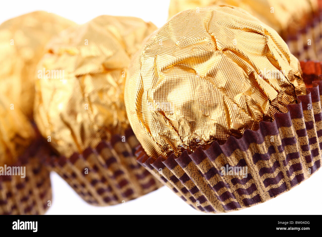 Several golden luxury sweets isolated on white Stock Photo - Alamy