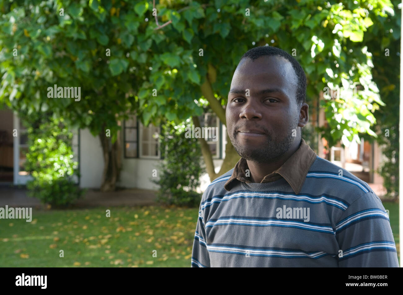 Portrait of a South African man smiling, standing outside his house ...