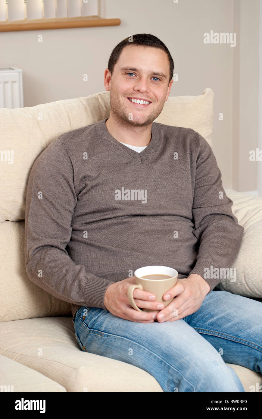Relaxed man sitting on sofa at home Stock Photo - Alamy