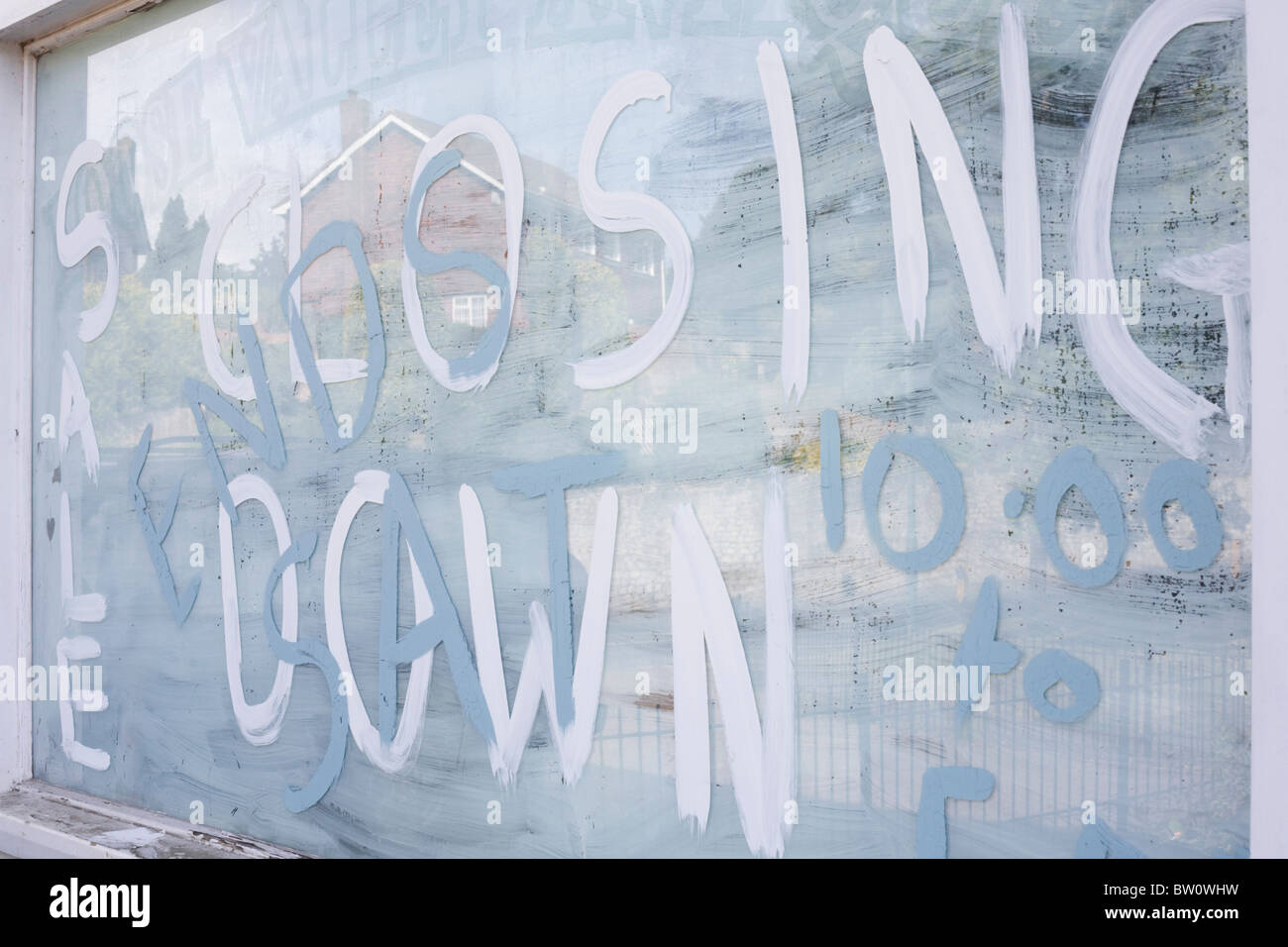 A closing down sale window is written on smeared whitewashed glass on a ...