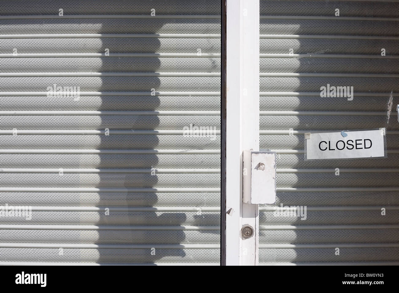A closed sign is stuck to the glass and metal shutters have been rolled ...
