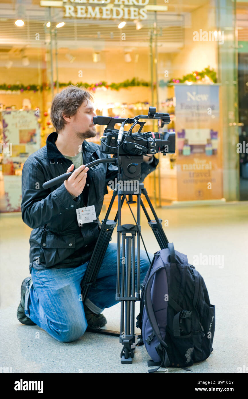 St Pancras Station , young bearded cameraman prepares for shoot of a TV ...