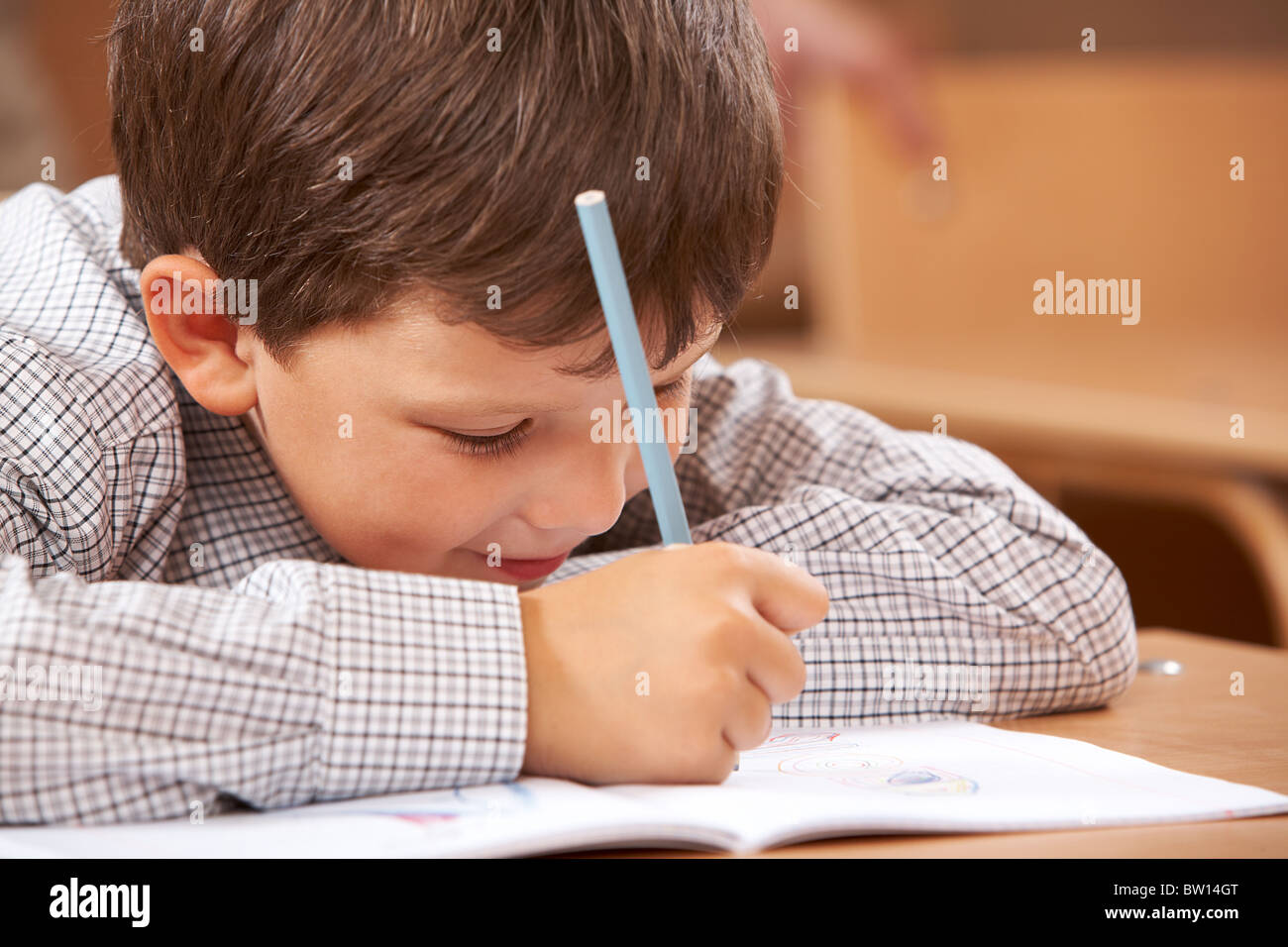 Photo of clever schoolkid writing something in his copybook at lesson ...
