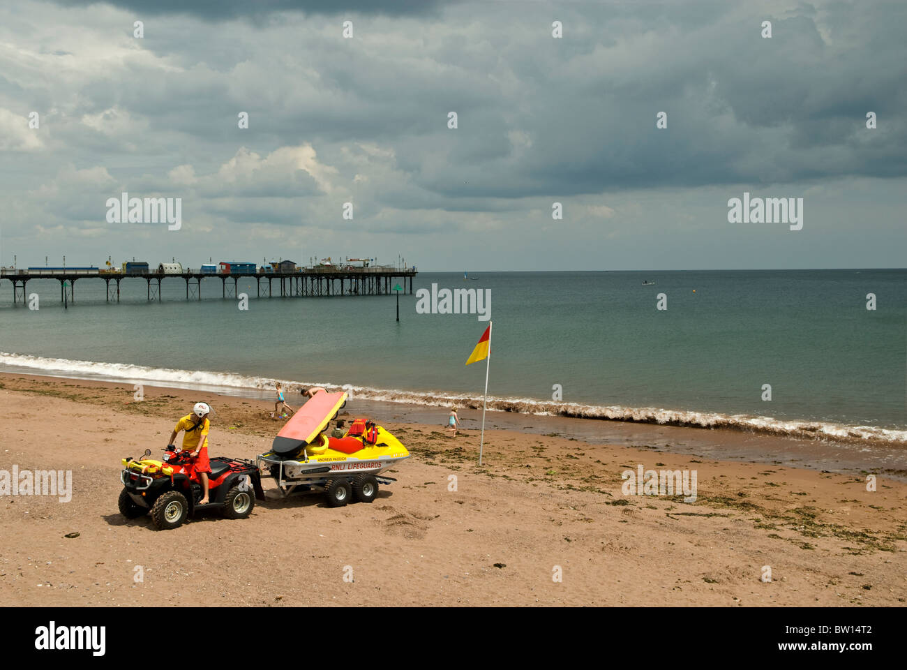 RNLI Lifeguard on a quad bike pulling a jet ski behind on Teignmouth ...