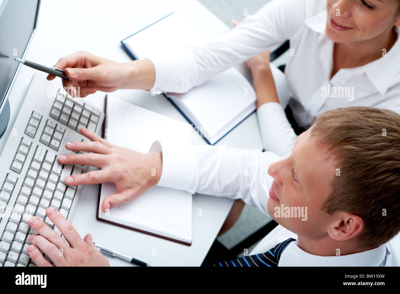 Photo of female pointing at monitor with typing man near by during ...