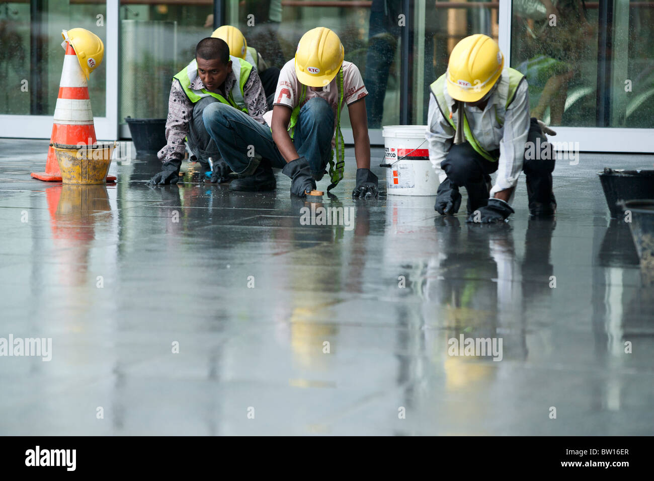 Migrant workers clean the floor in front of a shopping mall in ...