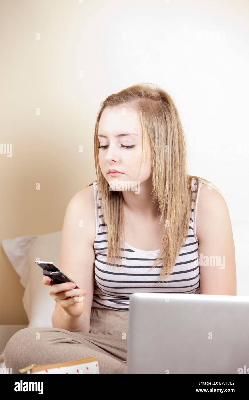 A teenage girl texts whilst on a laptop in her bedroom UK Stock Photo ...