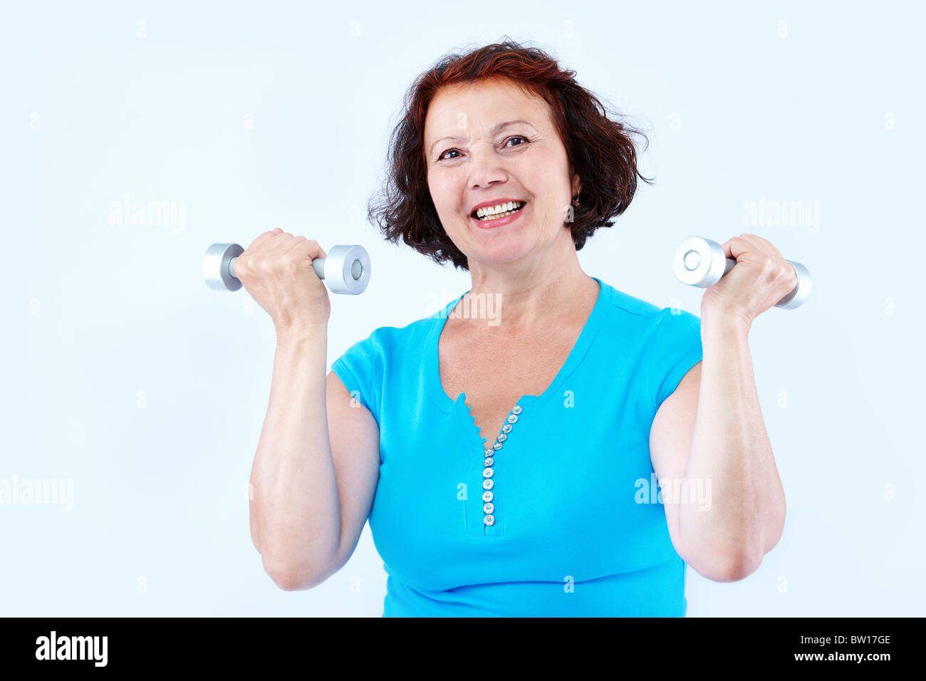 Portrait of middle-aged female doing physical exercise with dumbbells ...