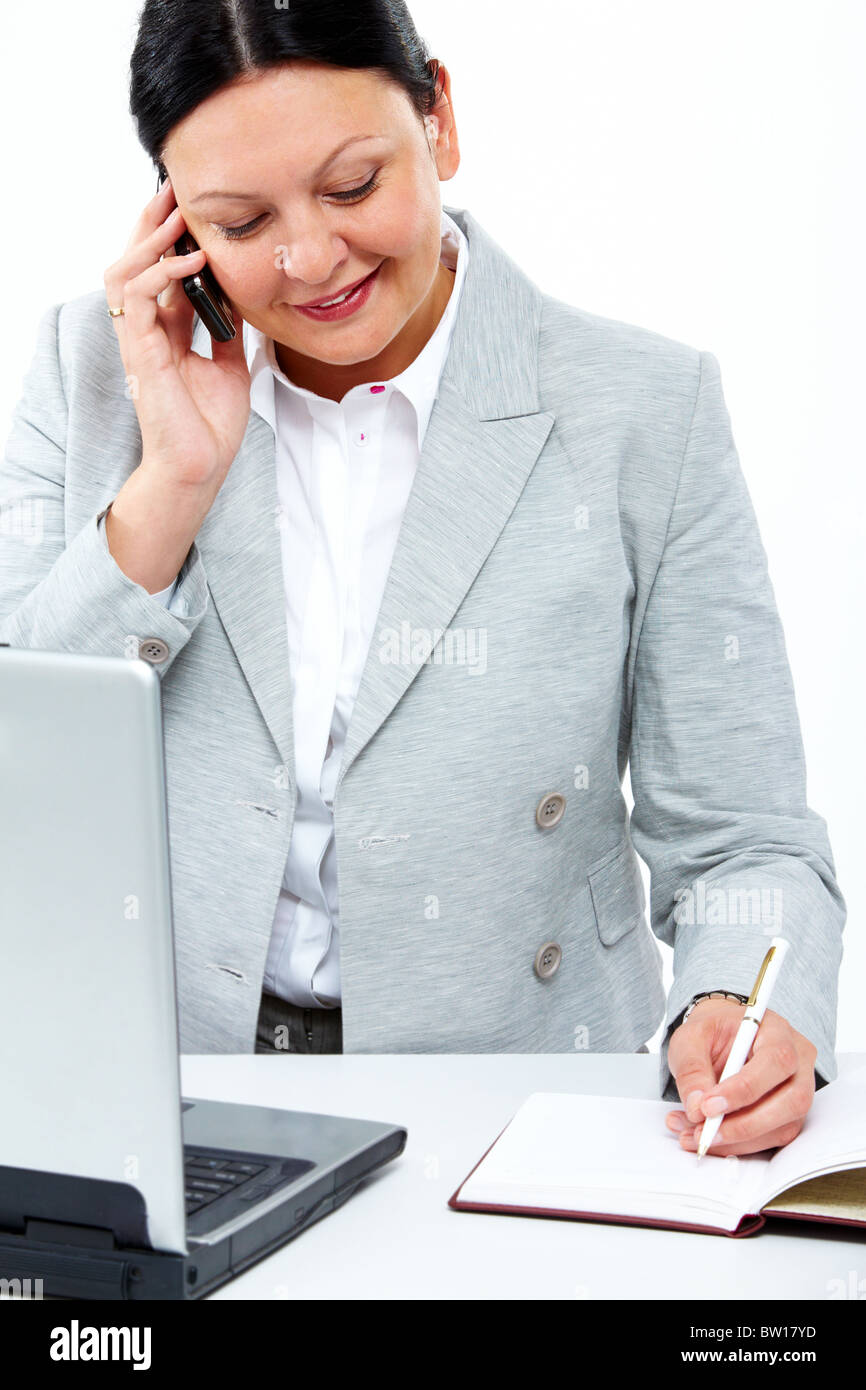 Busy secretary speaking on the phone and making notes in notepad with ...