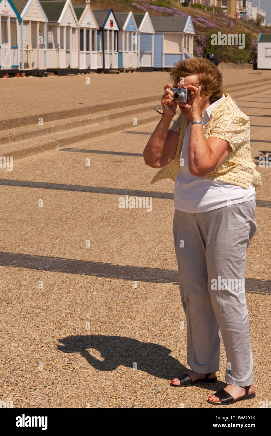 A woman taking a picture with her camera on the seafront in Southwold ...