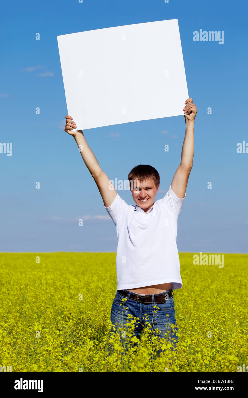 Portrait of happy guy with blank paper standing in meadow Stock Photo ...