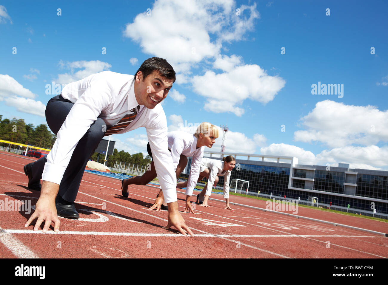 Row of business people getting ready for race with man at foreground ...