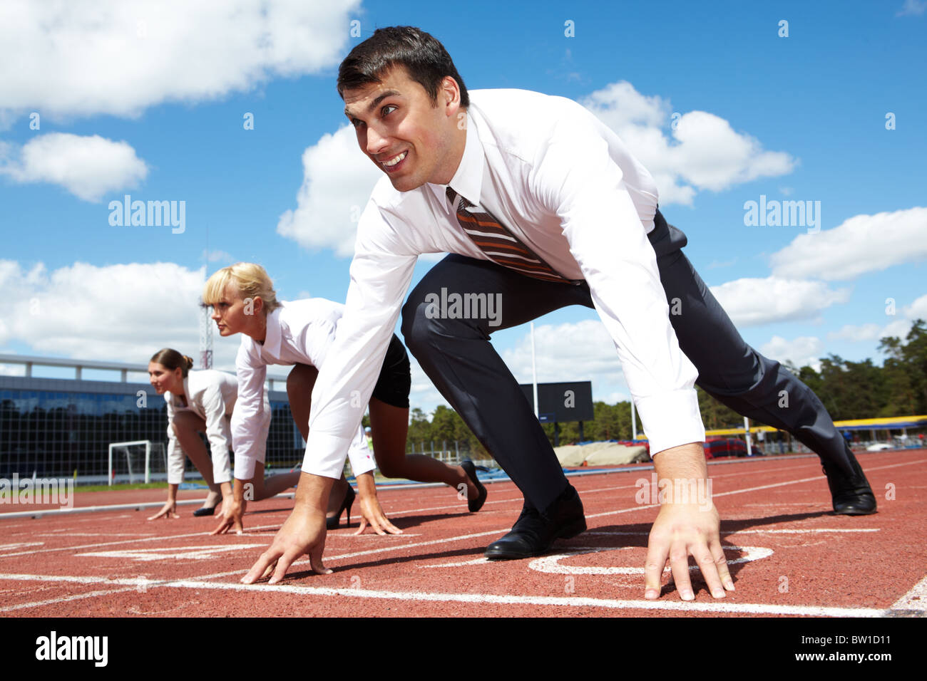 Image of businessman getting ready for race with two females on ...