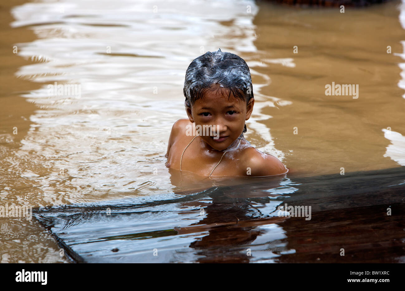 Street scene of floods in Siem Reap. Girl wash head in water. Cambodia ...