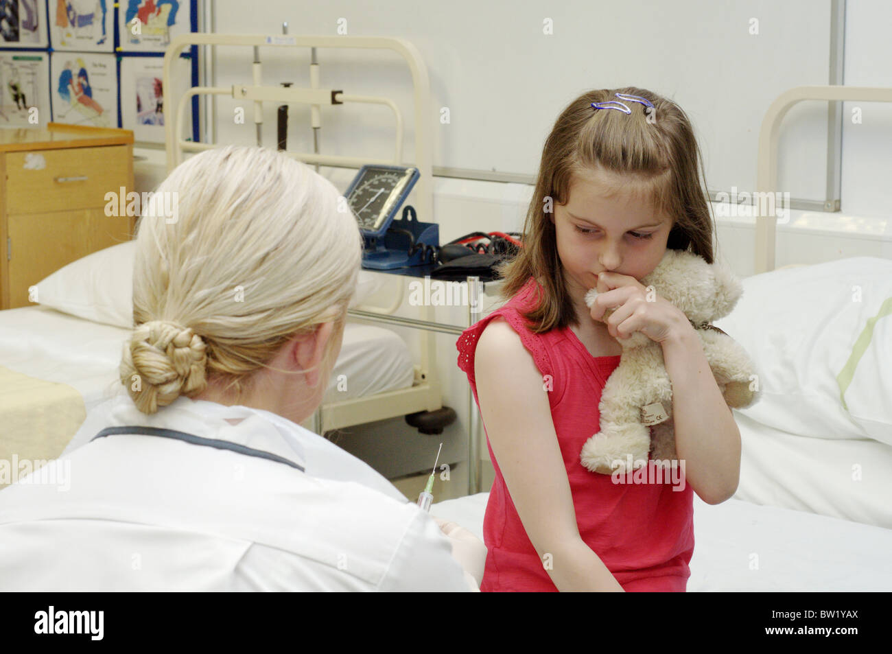 A child being given an injection in a hospital ward by a female nurse ...