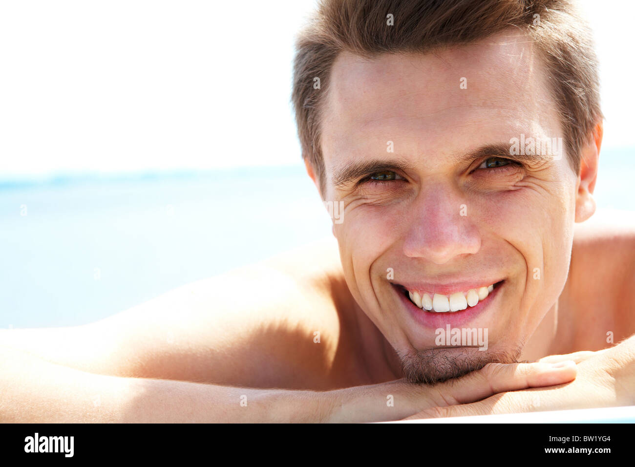 Photo of smiling guy looking at camera while sunbathing Stock Photo - Alamy