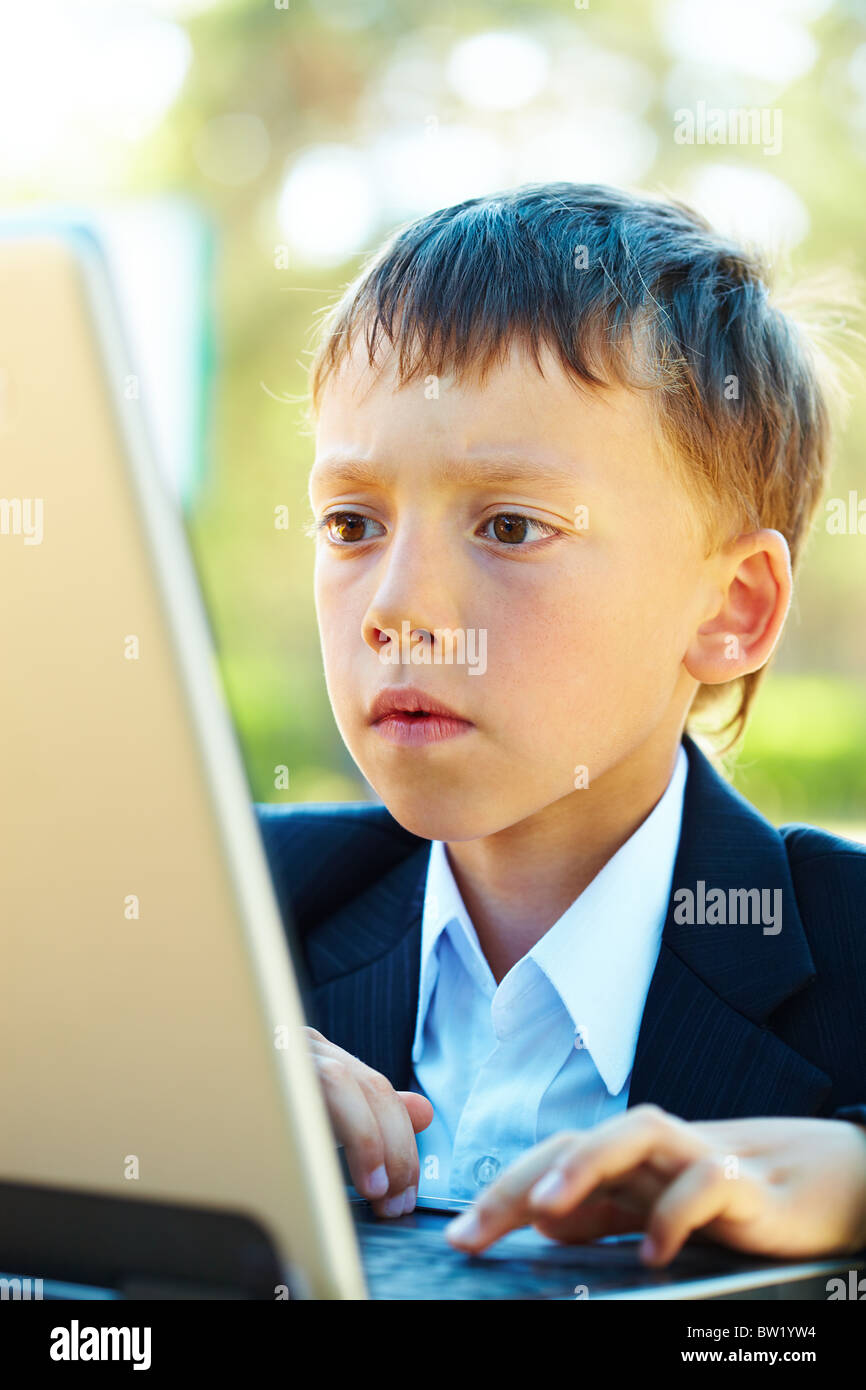 Portrait of smart boy working with laptop with attention Stock Photo ...
