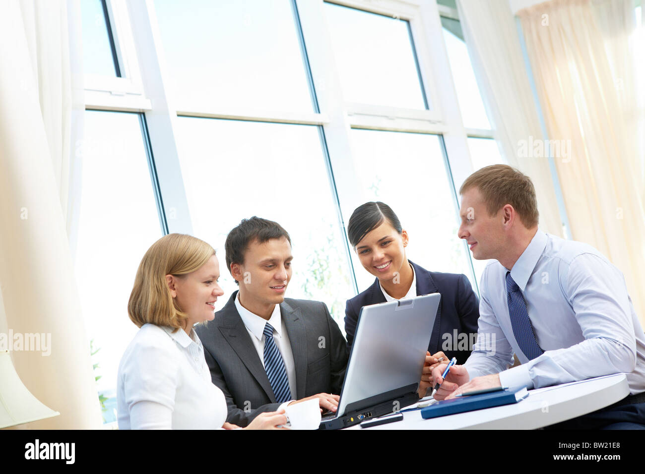 Photo of confident employees working round table in office Stock Photo ...