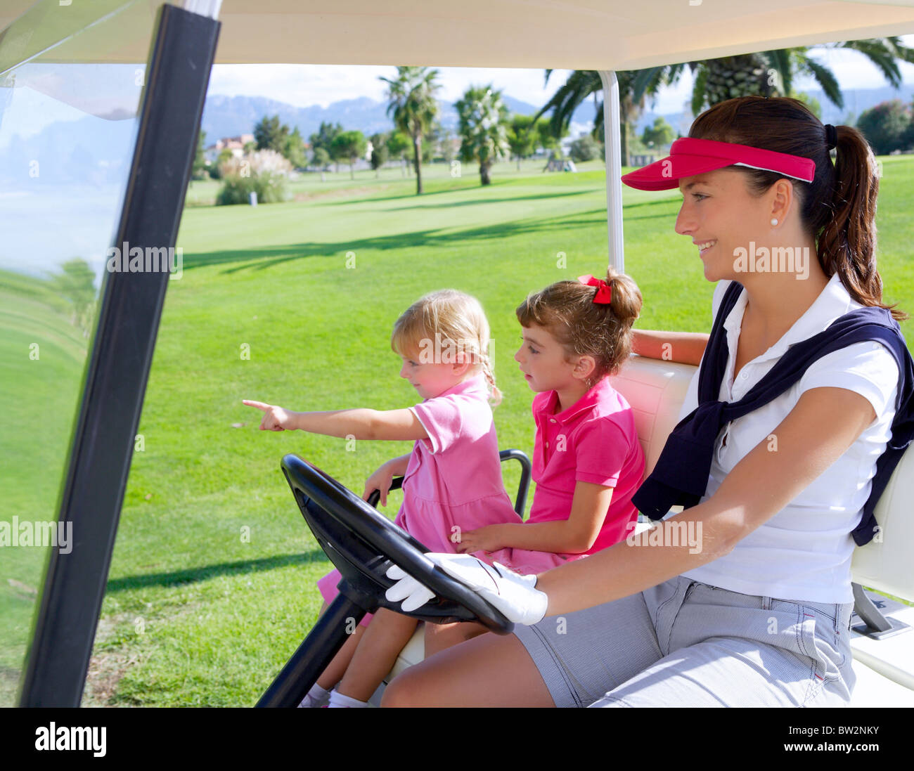 golf course family mother and daughters in buggy green grass field ...