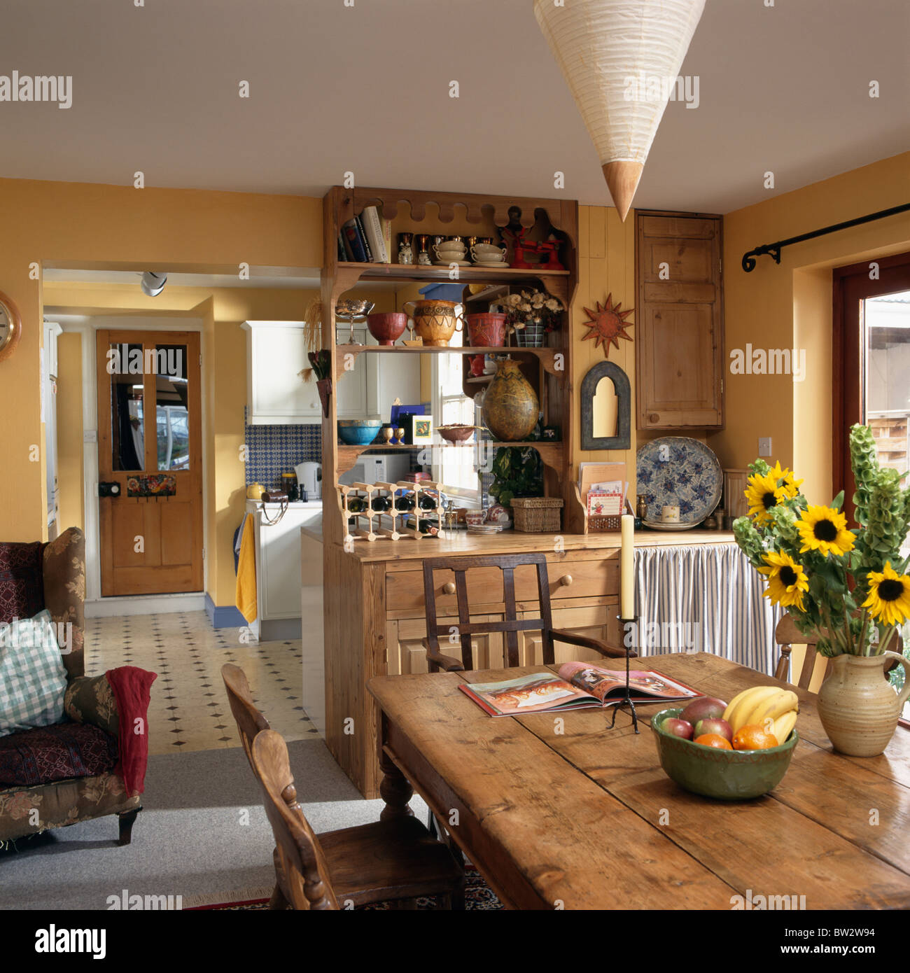 Vase of yellow sunflowers on old pine table in yellow kitchen dining ...