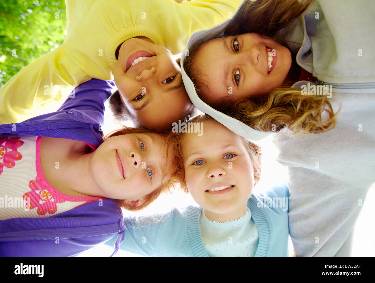 Below view of several happy girls standing head by head to each other ...