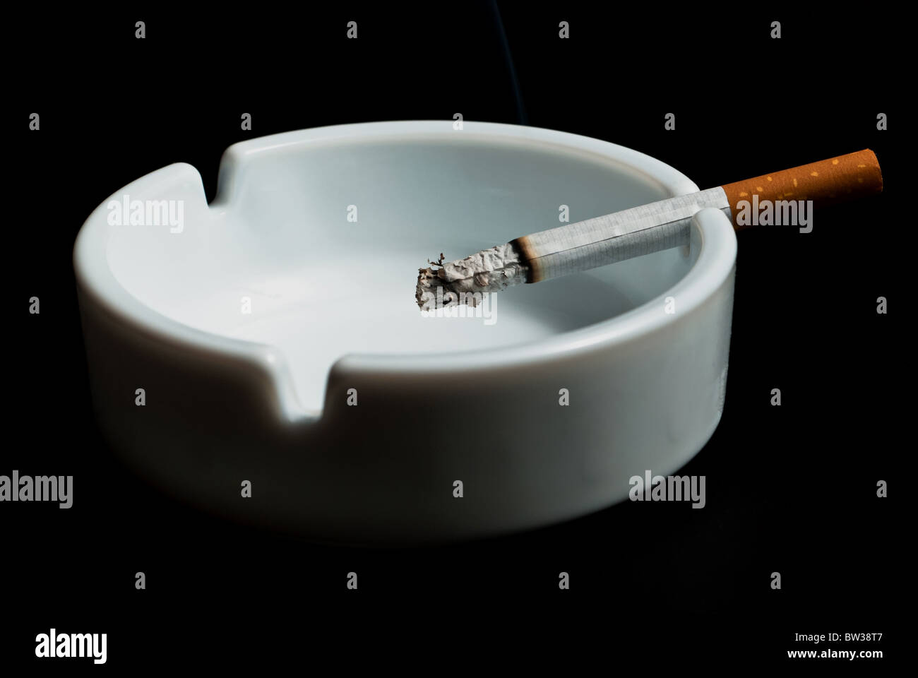 burning cigarette in the ashtray white on black background Stock Photo ...