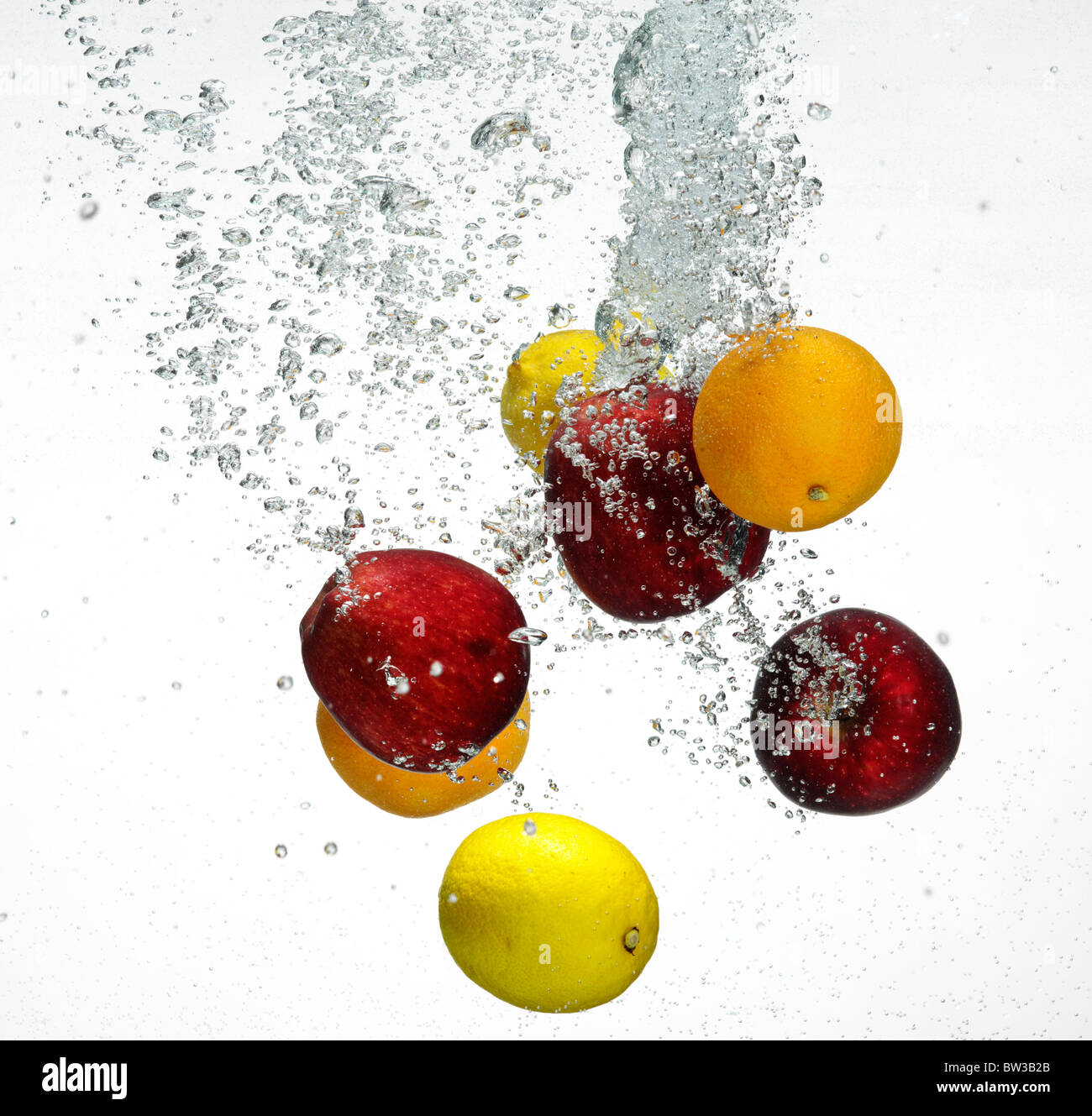 Fruit falling in water on a white background Stock Photo - Alamy
