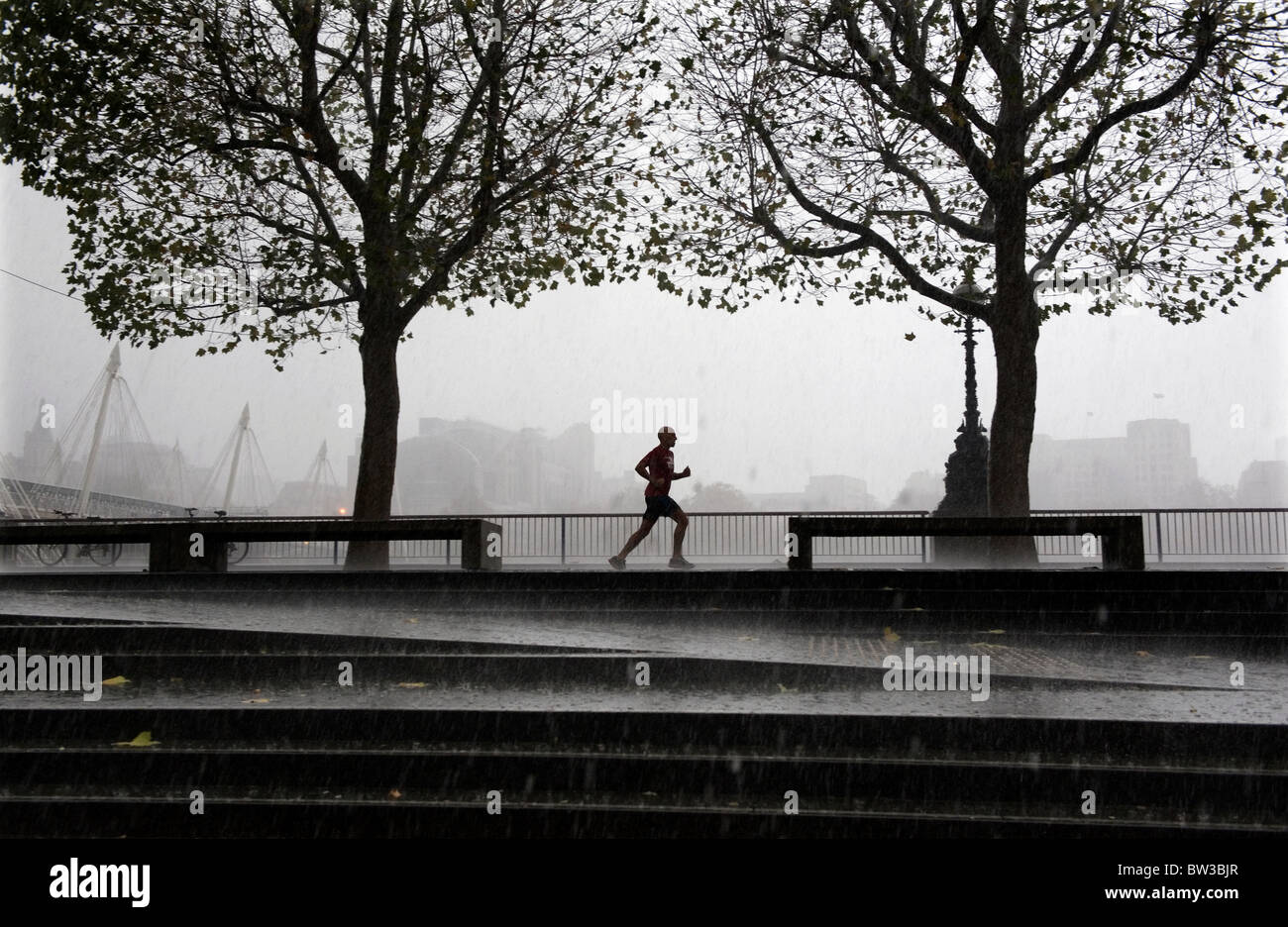 A rainy day in London, Britain. A man jogs during heavy rain storm ...
