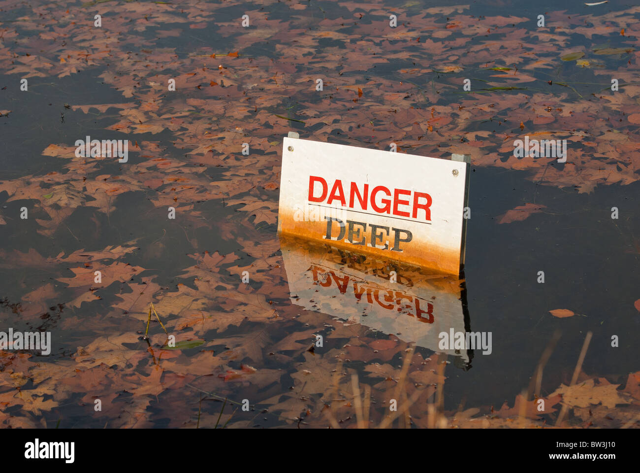 deep water warning sign in pond where water level is obscuring the ...