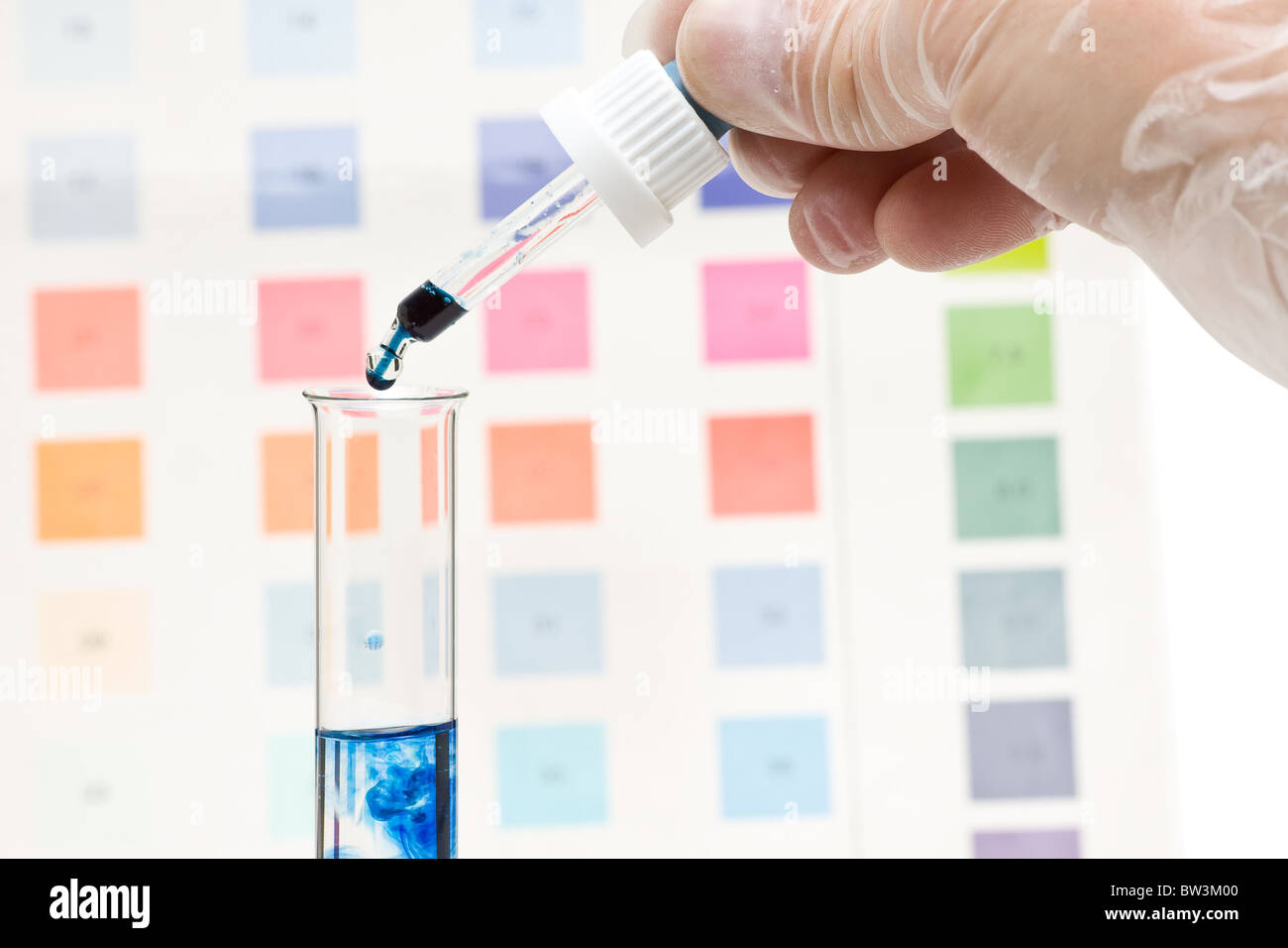 Hand dripping pH indicator into test tube with visible color change in ...