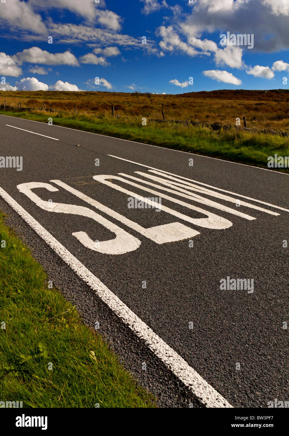 Slow sign painted on country road in the UK to warn motorists to slow ...