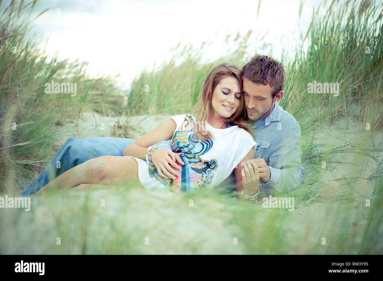 Young couple cuddle on sand dunes Stock Photo - Alamy