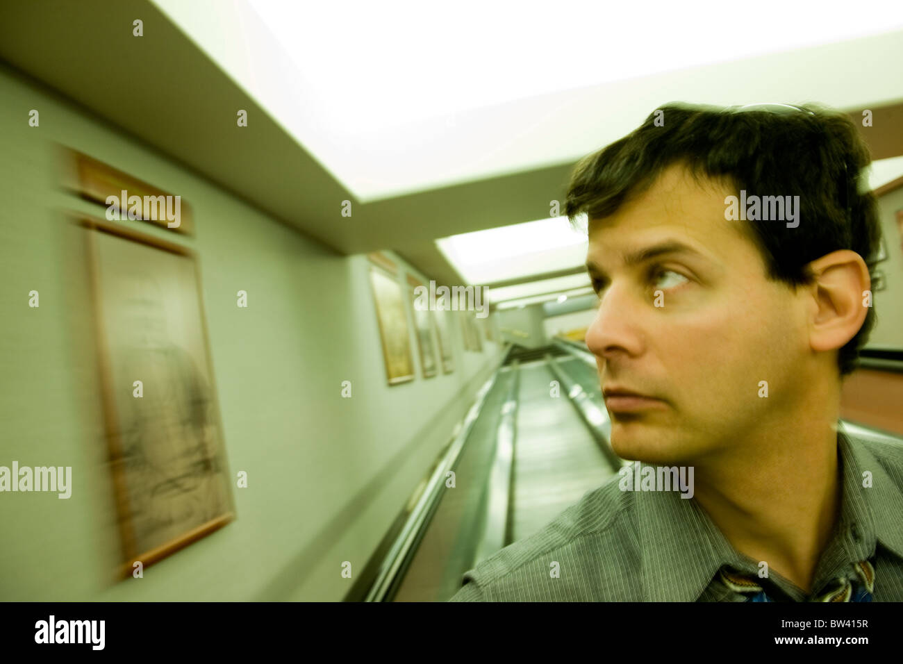 Young man standing on a moving walkway Stock Photo - Alamy