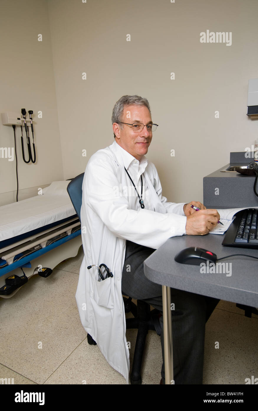 Doctor sitting in chair at desk in hospital examination room, Toronto ...