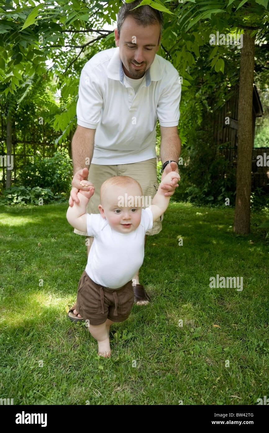 Baby boy learning to walk with the help of his Dad, Ontario Stock Photo ...