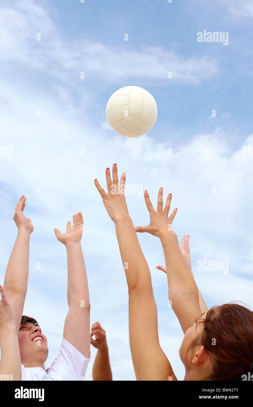Photo of teenage friends playing with ball on background of cloudy sky ...