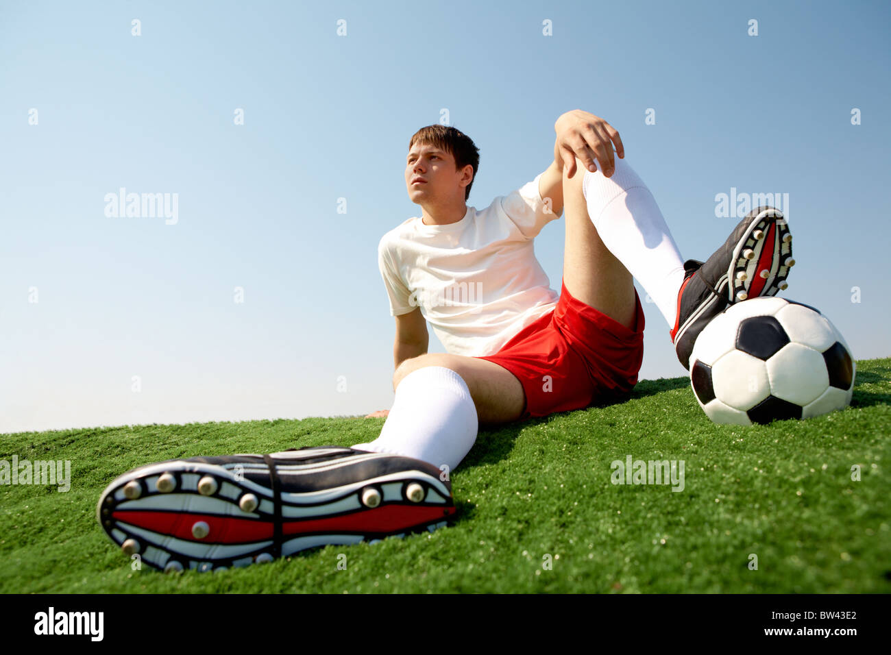 Photo of soccer player sitting on green grass-field and resting Stock ...