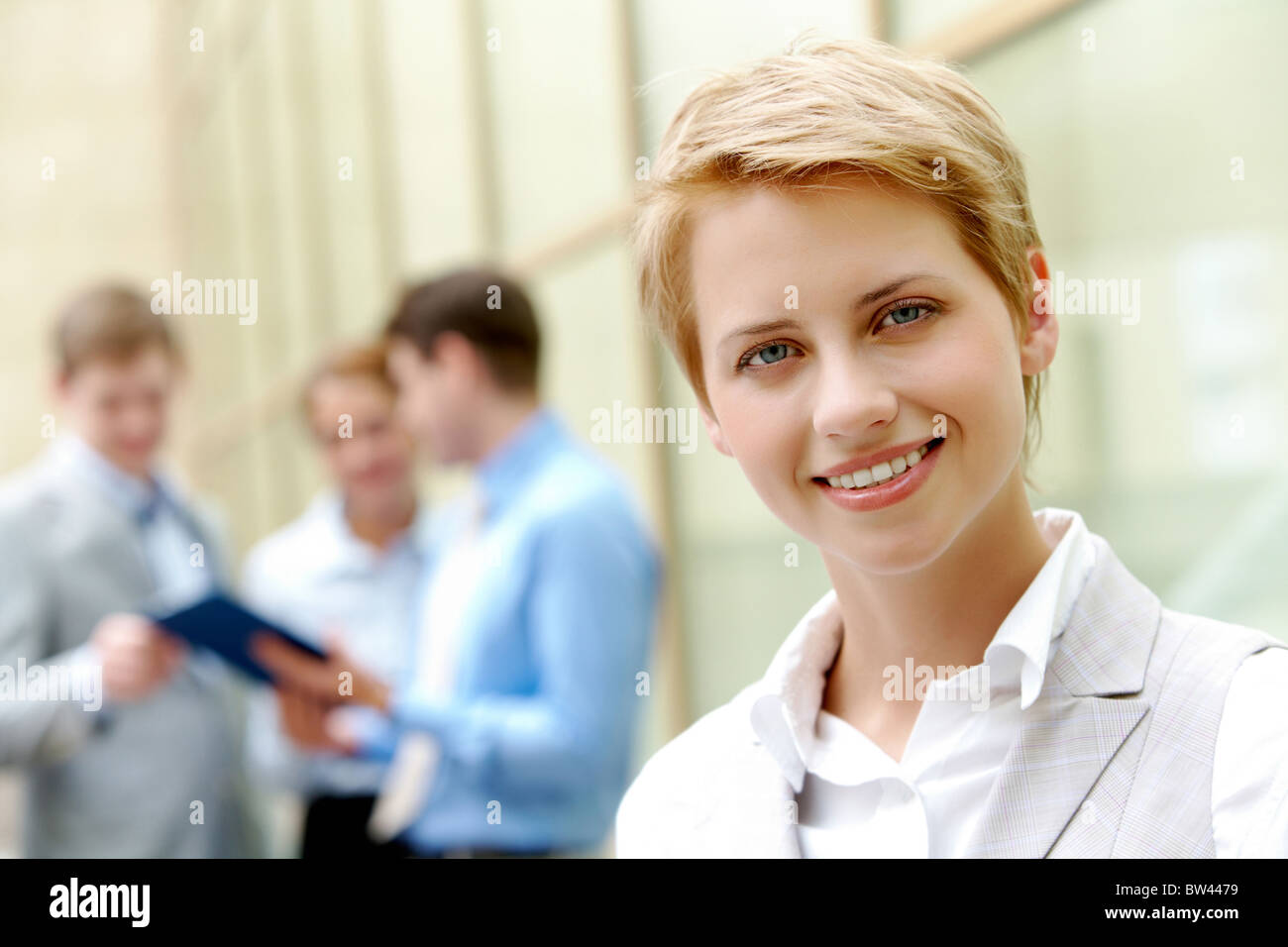 Portrait of pretty employee smiling at camera in natural environment ...