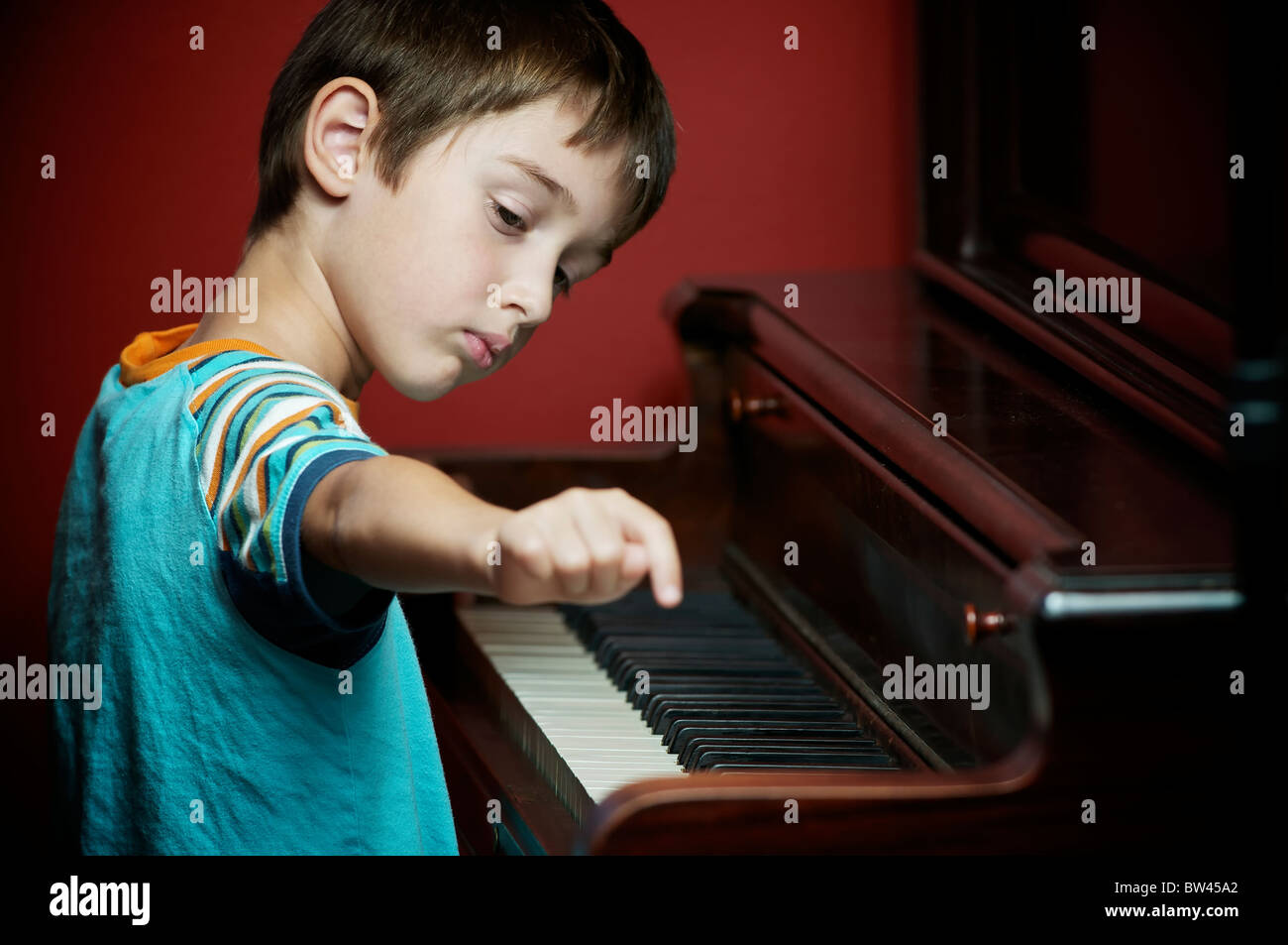 Young boy hitting note at an old piano Stock Photo - Alamy