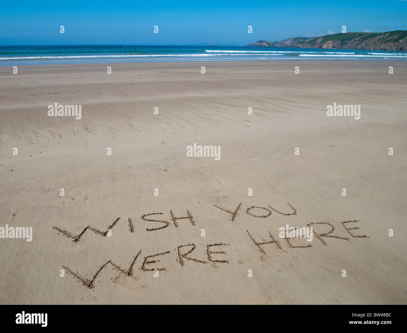 writing in the sand on a beach with the sea in the distance and a blue ...