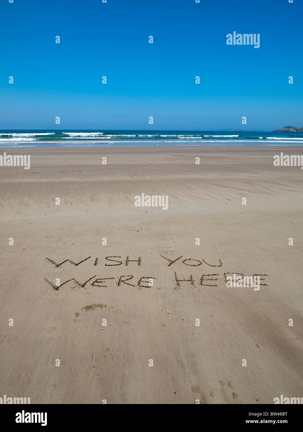 writing in the sand on a beach with the sea in the distance and a blue ...